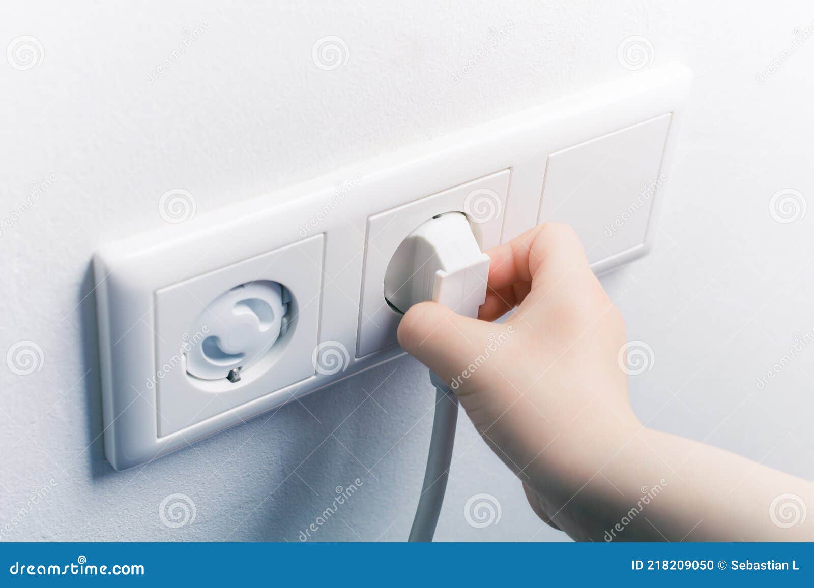 Child Hand Pulling a Power Cord Out of a Wall Socket with Safety Plugs ...