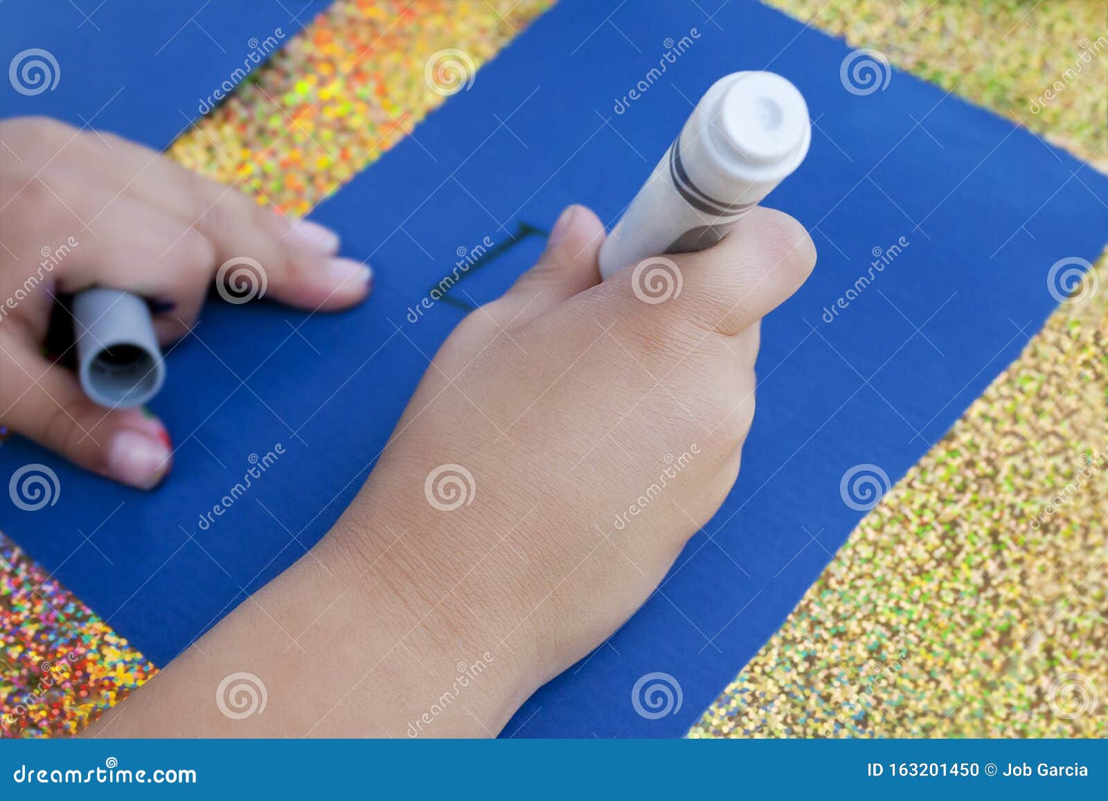 Child Holding a Marker and Writing on a Blue Paper Stock Photo - Image ...