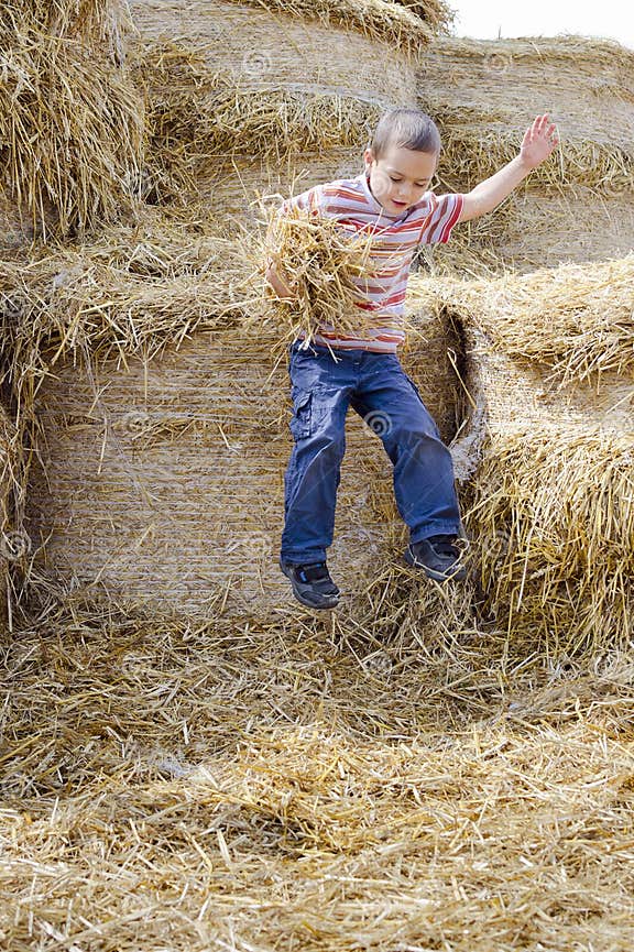 Child jumping in haystack stock image. Image of field - 65308499