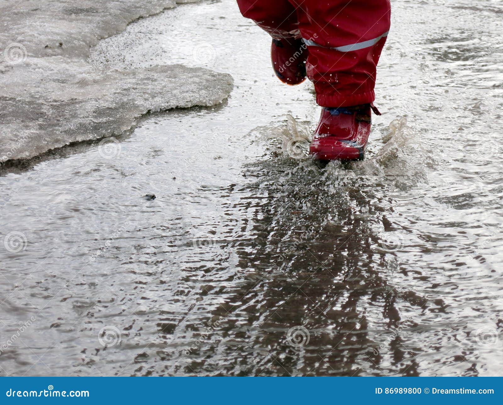 Child Jumping for Puddles on the Roads Thaw in the End of Winter Stock ...