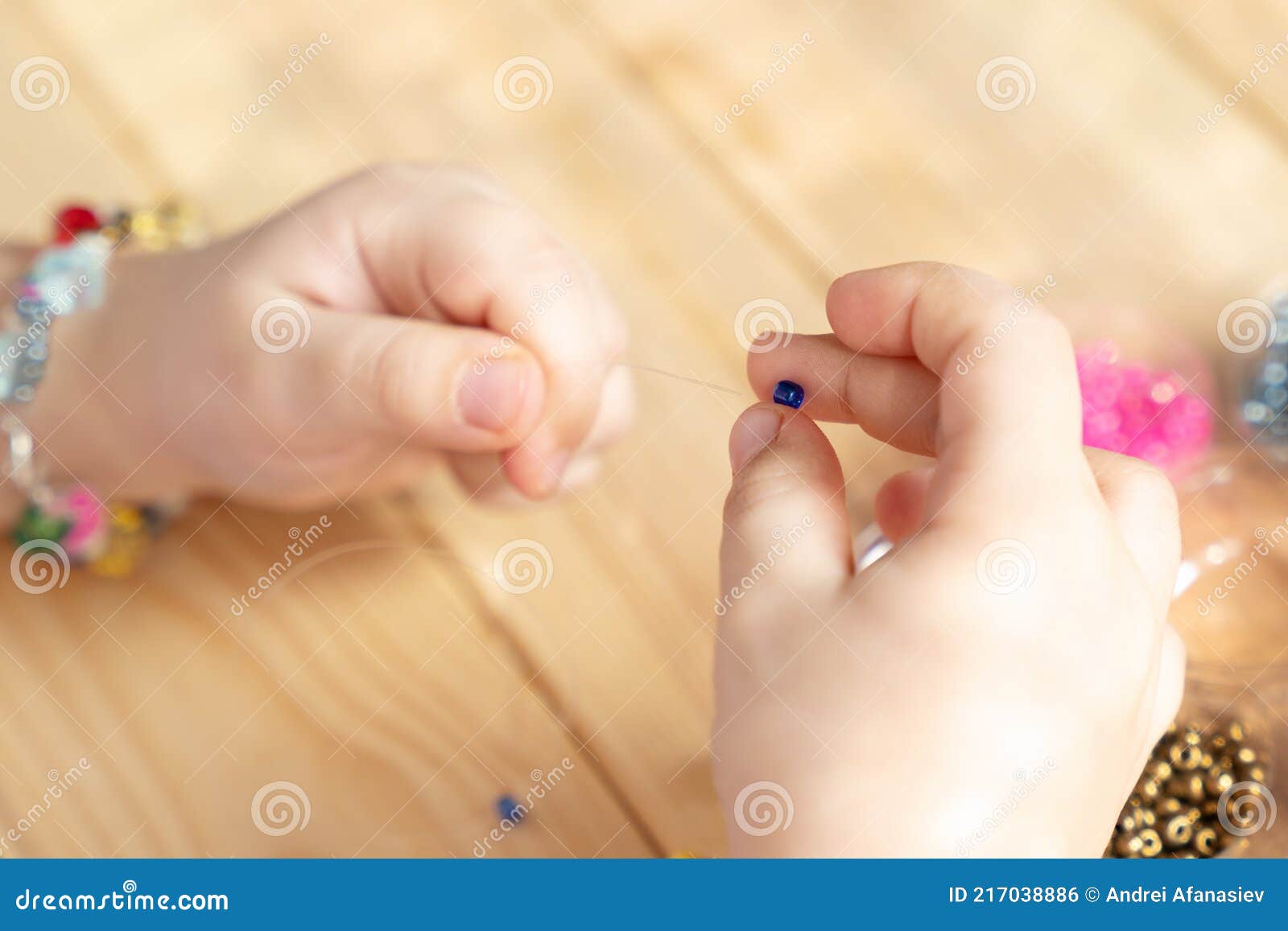 The Child Makes Jewelry with His Own Hands, Stringing Colorful Beads on ...