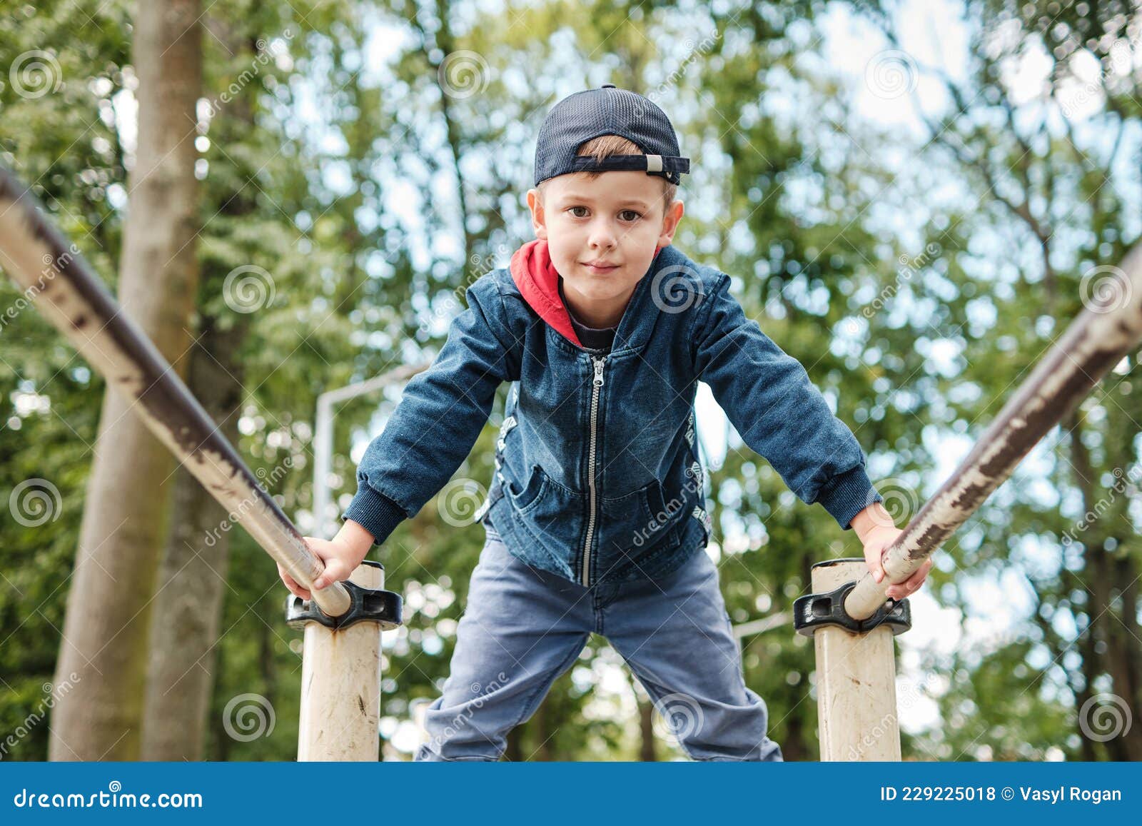 The Child Performs Exercises on Parallel Bars on the Street. Active ...