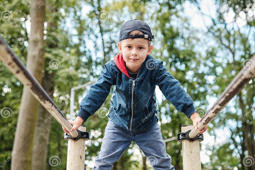 The Child Performs Exercises on Parallel Bars on the Street. Active ...