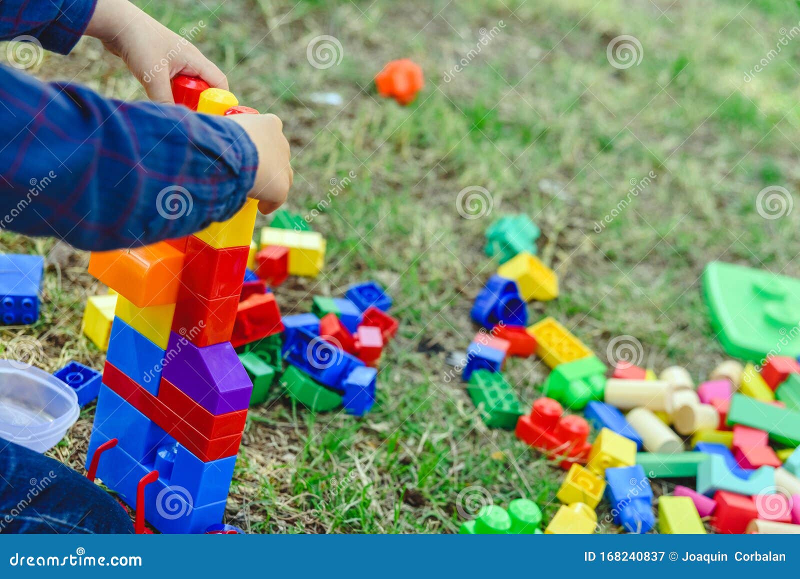 Child Playing with Colorful Blocks Sitting on the Ground of a Garden in ...