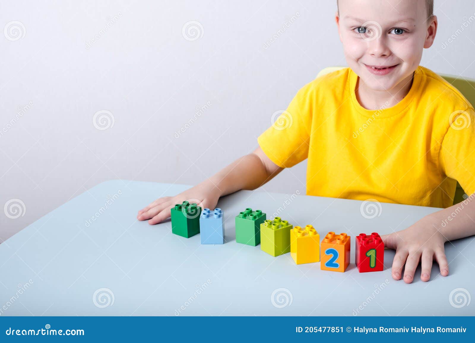 The Child Playing with Cubes with Colorful Numbers on the Table. on a ...