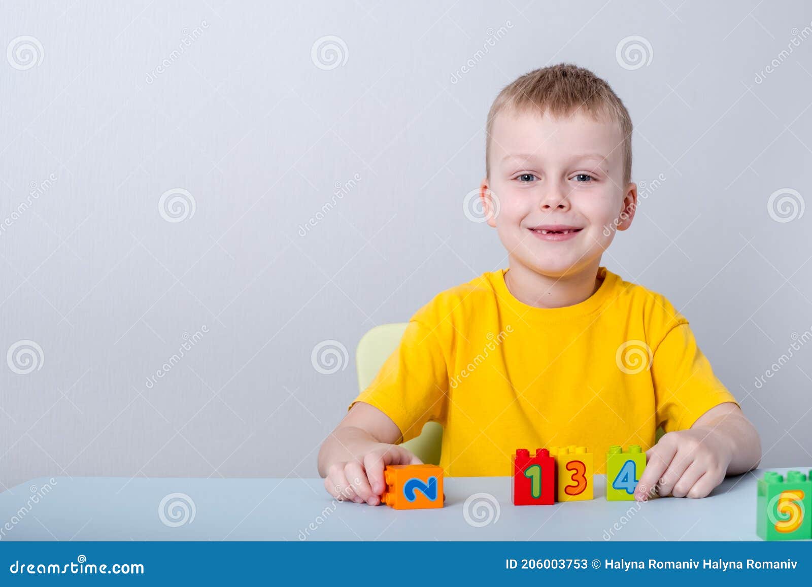 The Child Playing with Cubes with Colorful Numbers on the Table. on a ...