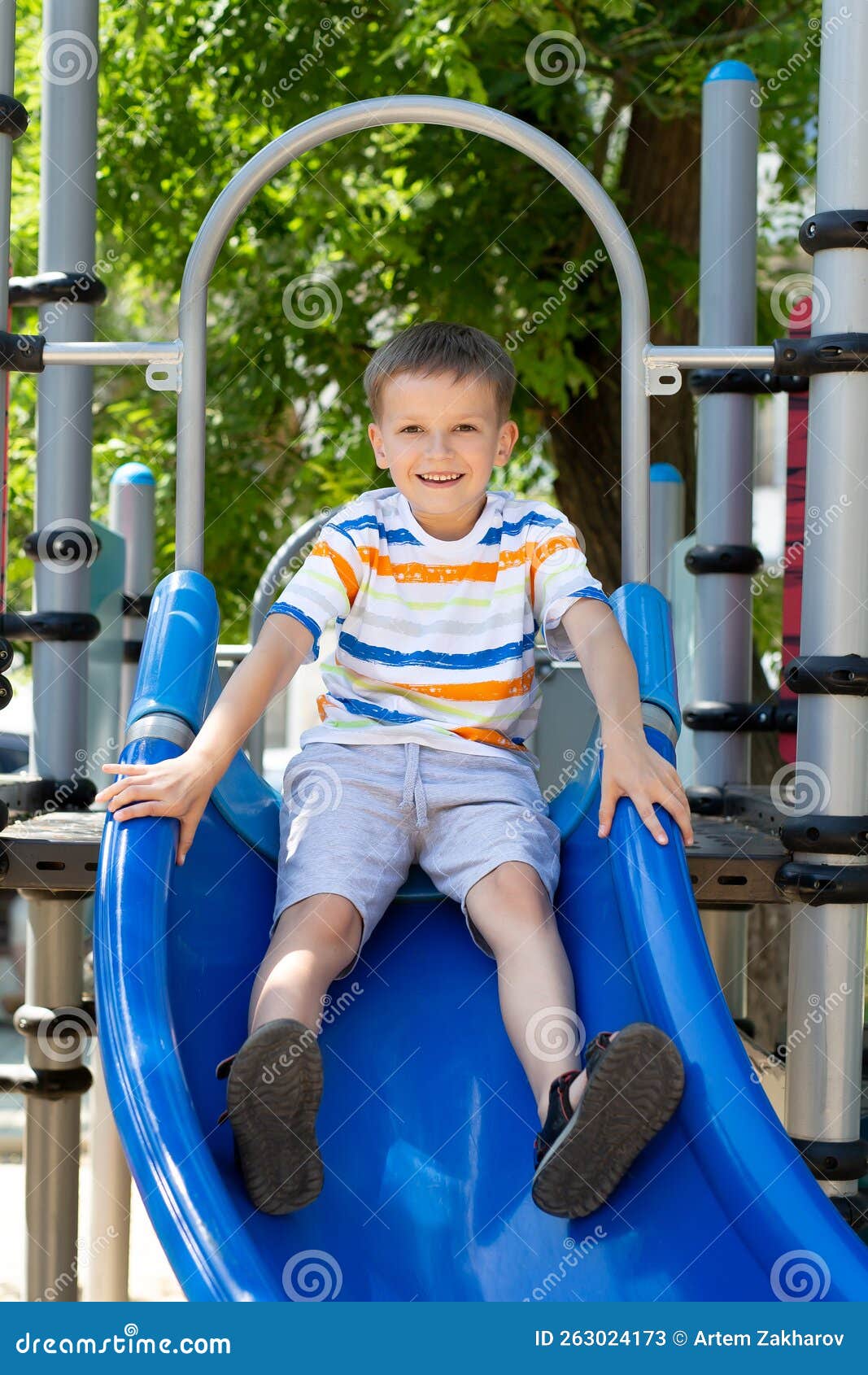 A Child is Playing on an Outdoor Playground. an Active Boy Rides Down a ...
