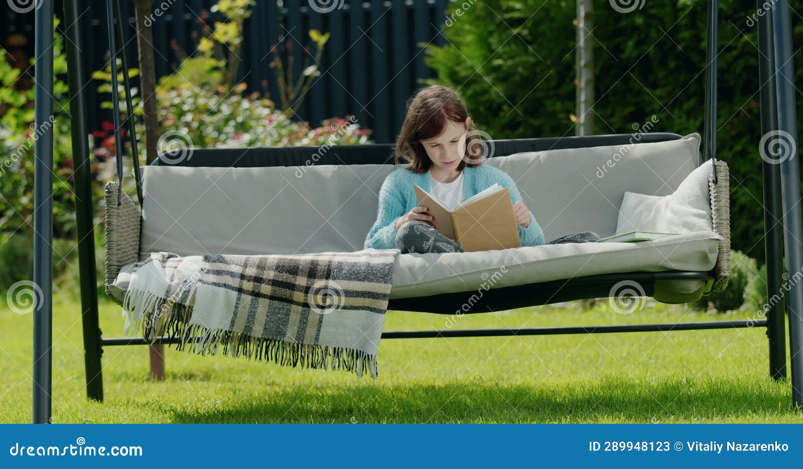 Child Reading a Book, Sitting in a Garden Swing in the Backyard of a ...