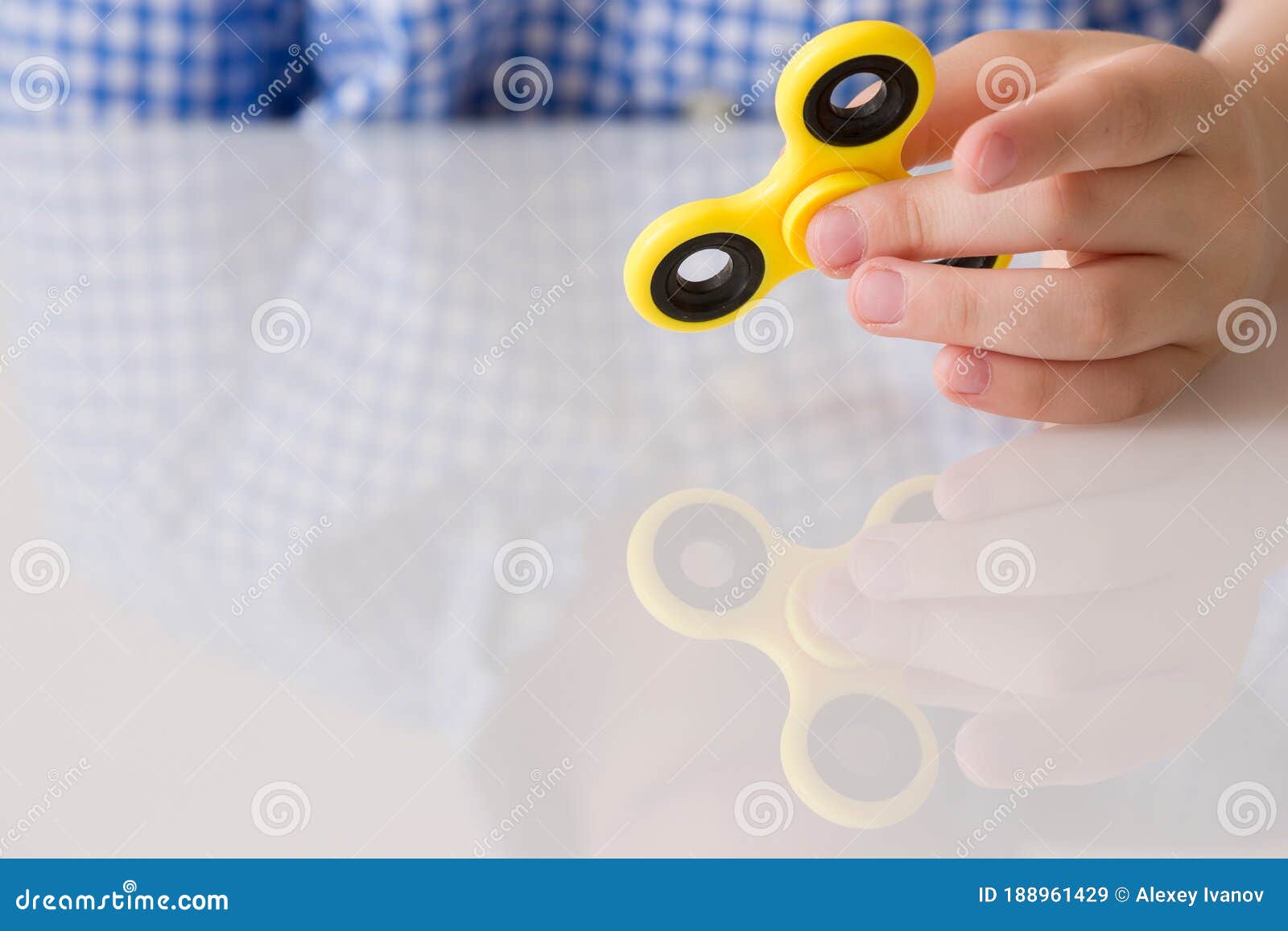Child`s Hand Spinning a Fidget Spinner Device. Playing with a Yellow ...