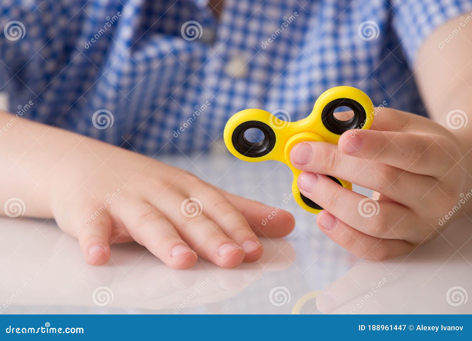 Child`s Hand Spinning a Fidget Spinner Device. Playing with a Yellow ...
