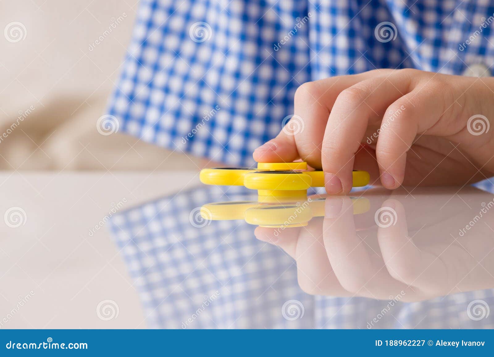 Child`s Hand Spinning a Fidget Spinner Device. Playing with a Yellow ...