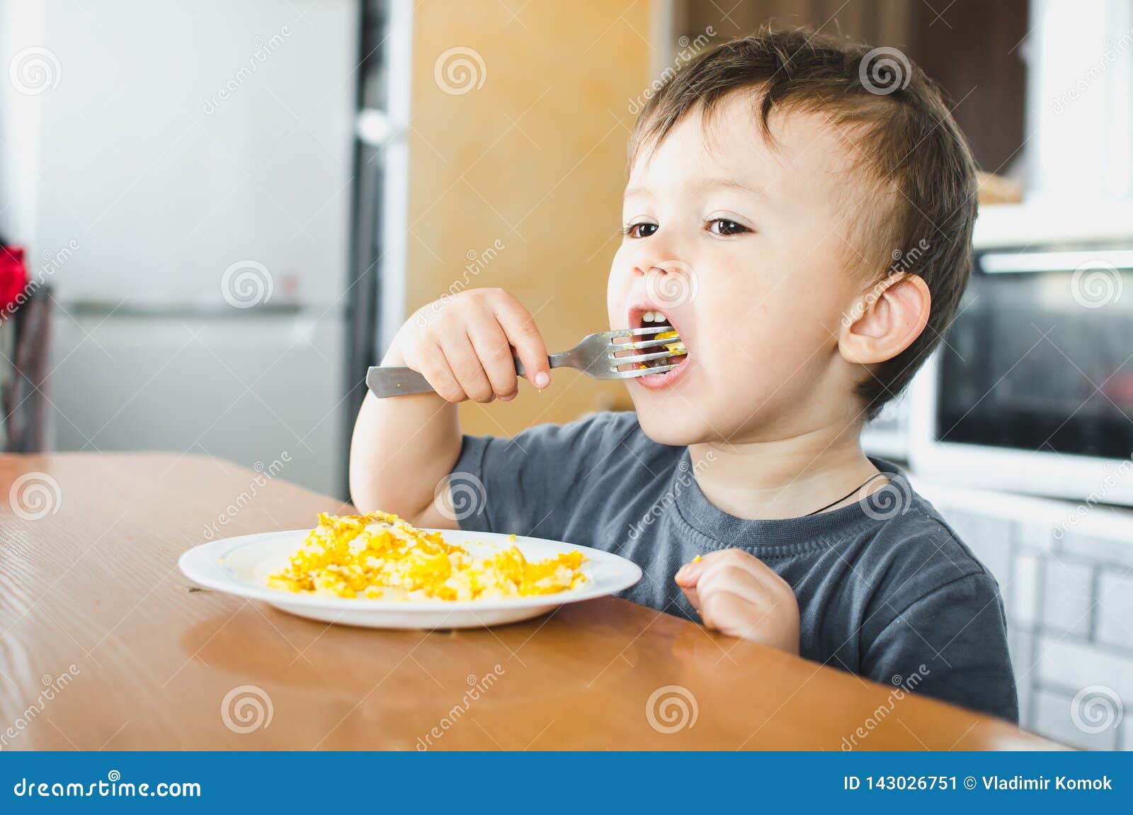 A Child in a T-shirt in the Kitchen Eating an Omelet, a Fork Stock ...