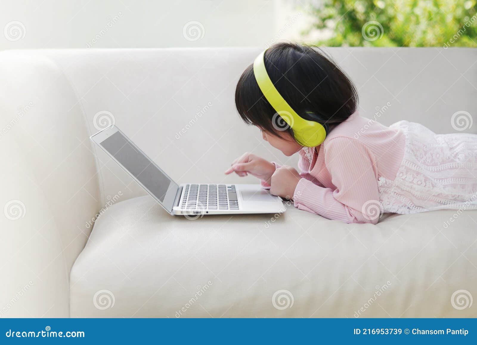 Child with Wireless Headphone Lying on Sofa Using Laptop Computer at ...