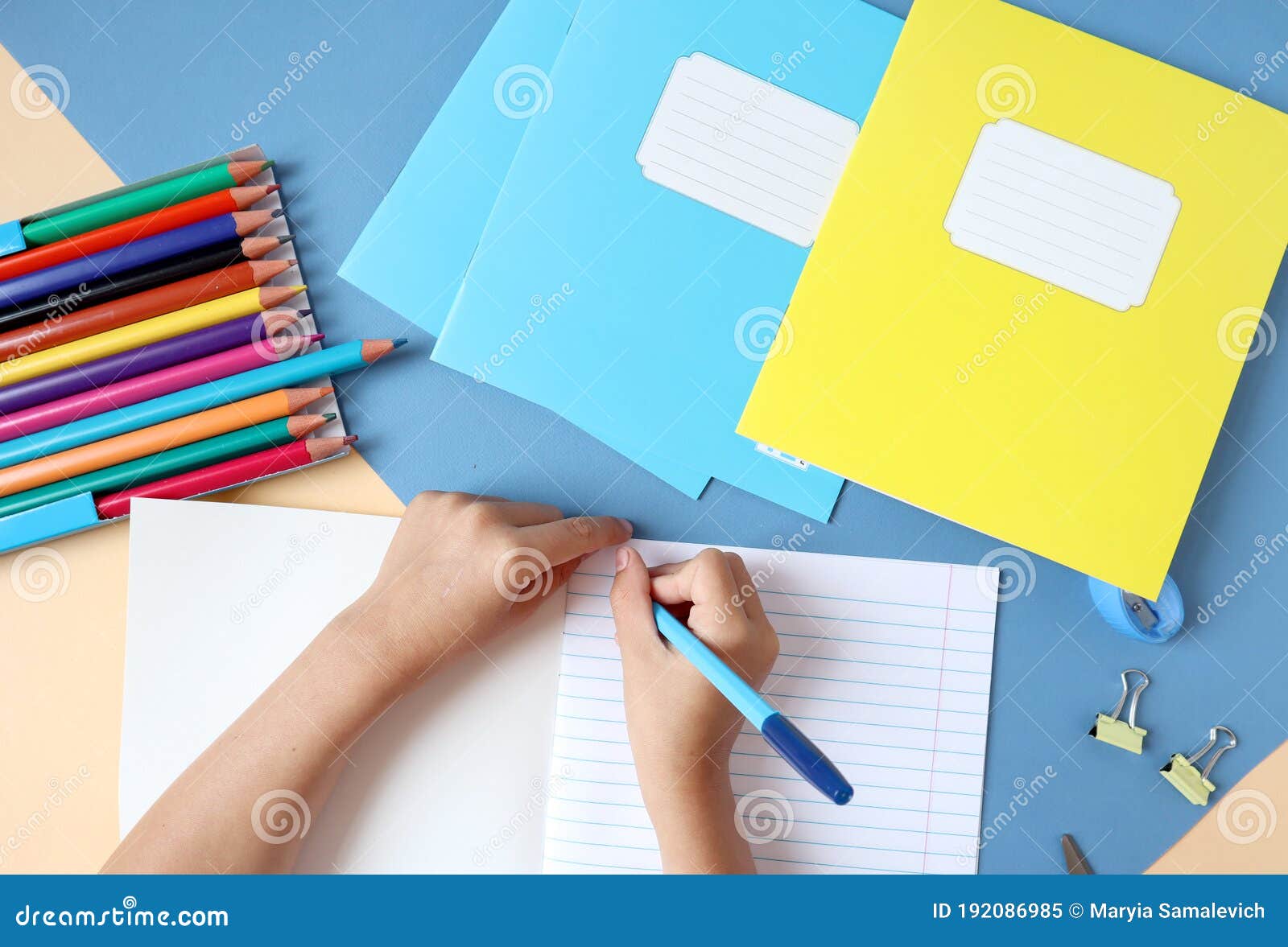 A Child Writes with a Pen in a Student`s Notebook on a Table with ...