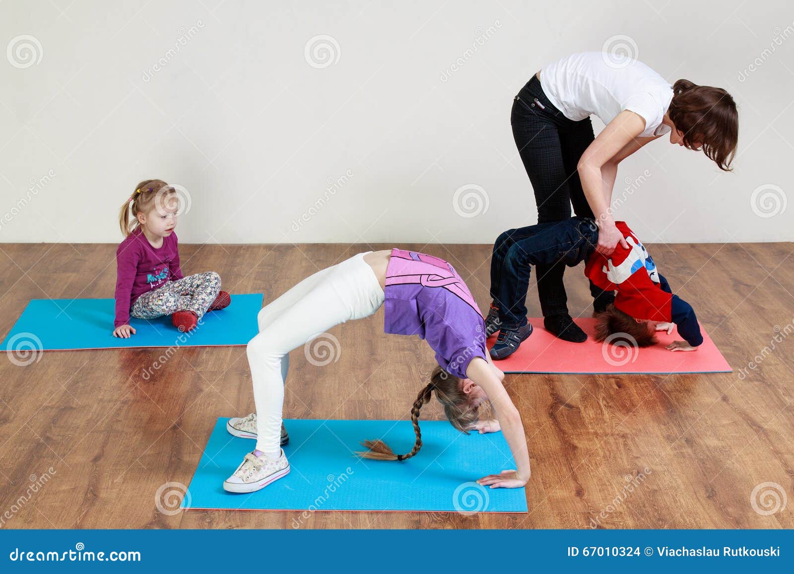 Children are Doing a Bridge Exercise with the Help of a Trainer Stock ...