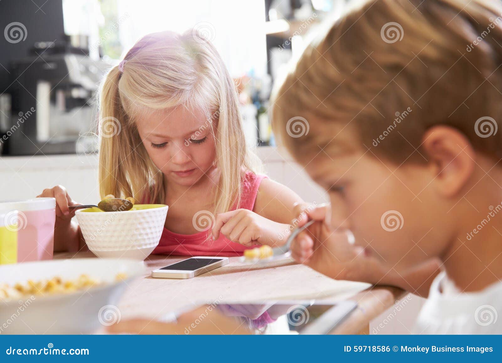Children Eating Breakfast Whilst Playing with Mobile Phone Stock Photo ...