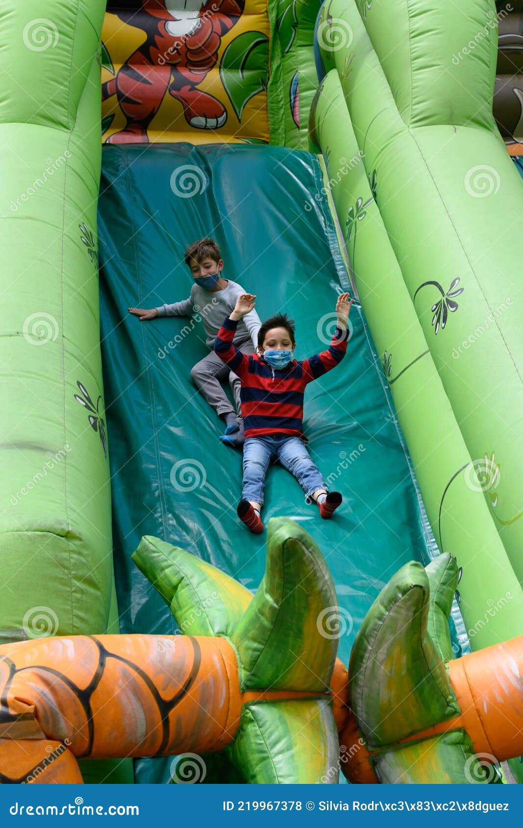 Children with Face Masks Have Fun while Going Down an Inflatable Slide ...