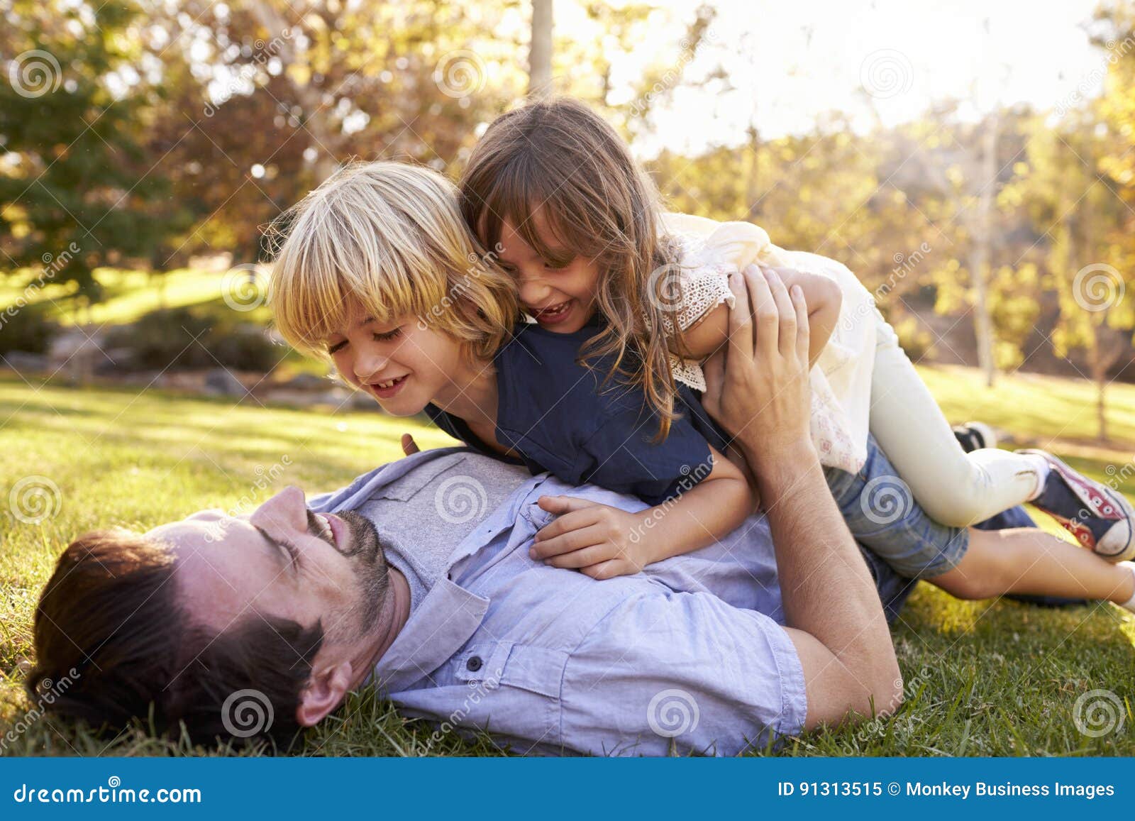 Children Jumping on Father in Park Stock Image - Image of parent ...