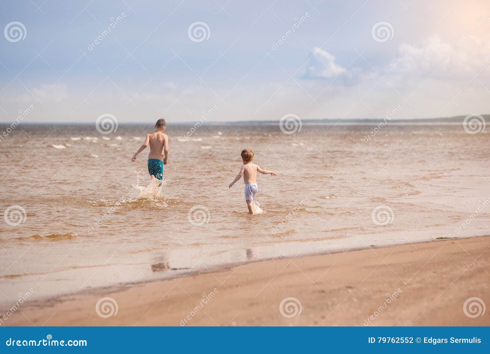 Children Run Along the Beach and Splatters with Water Stock Photo ...