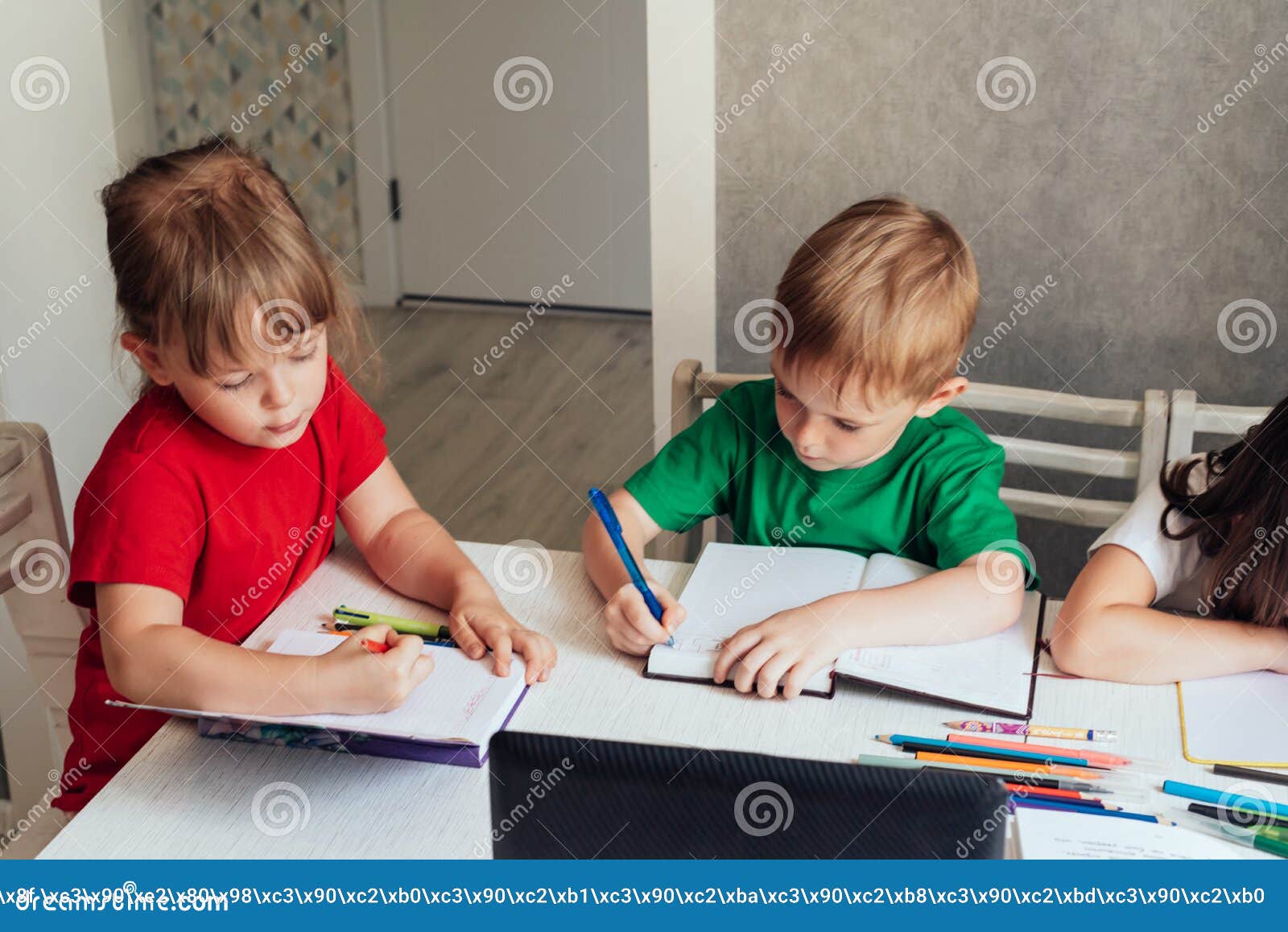 Children Sit at a Table and Write in Notebooks and Use a Laptop Stock ...