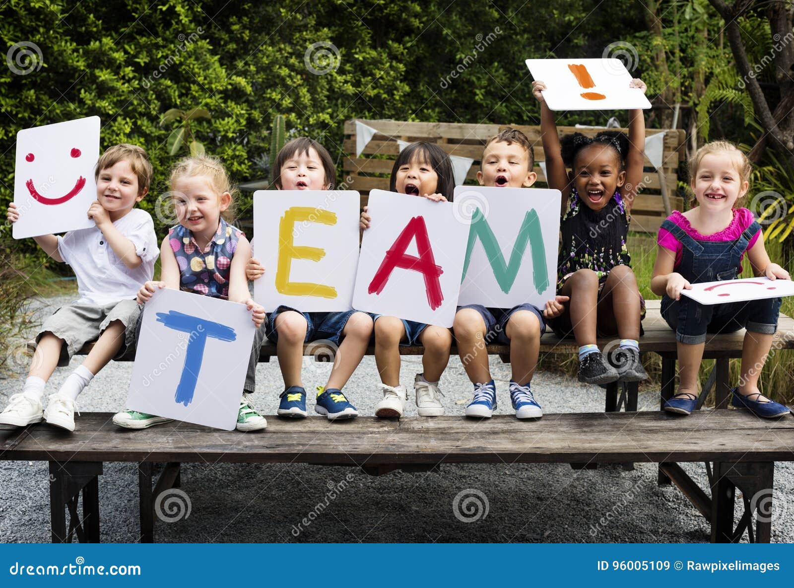 Children are Sitting on the Wooden Table Holding a Word Team Stock ...