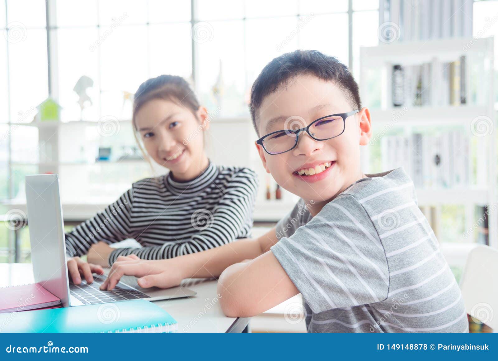 Children Using Notebook Computer at Library and Smiling at Camera ...