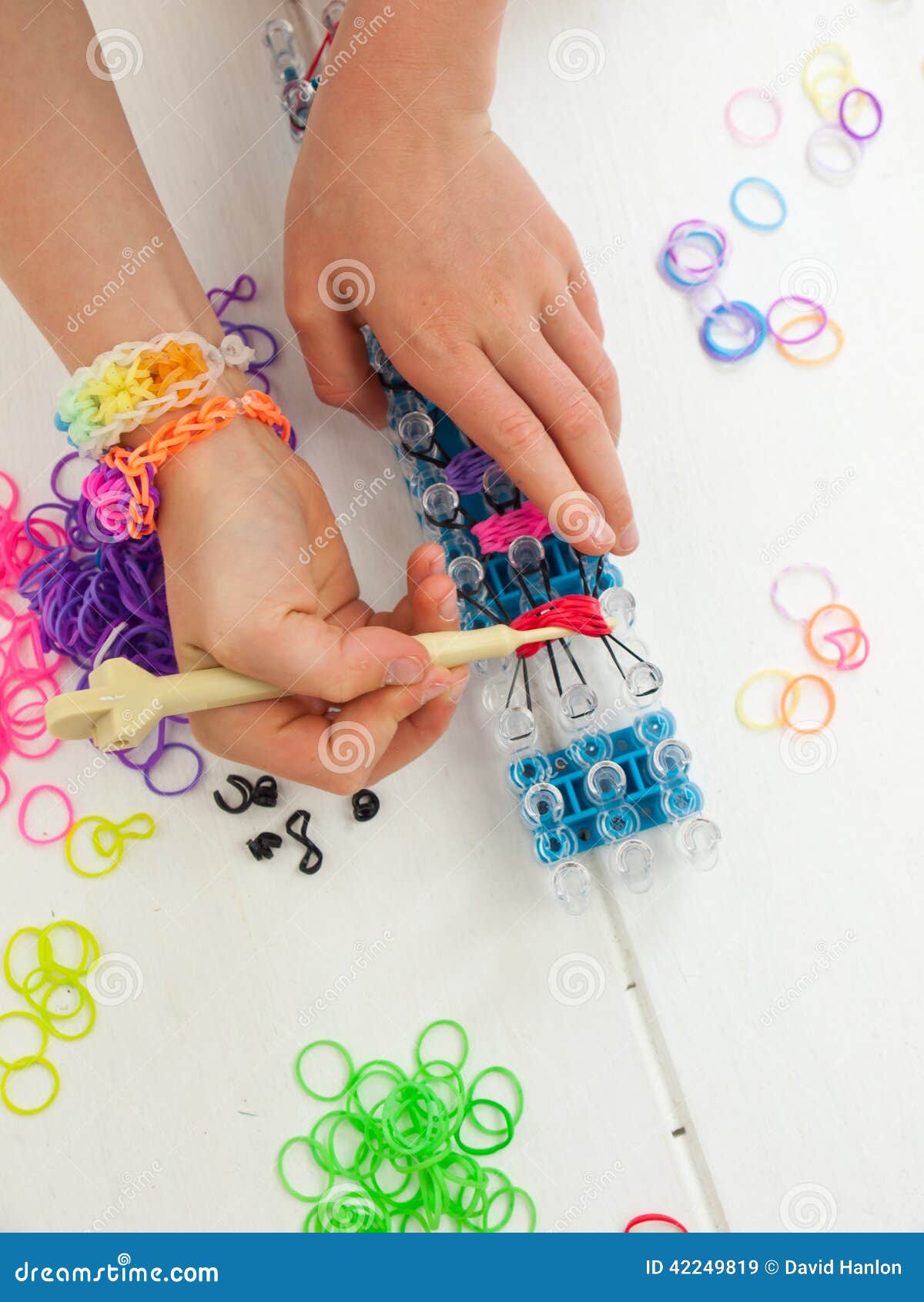 Childs Hands with Band Loom, Croche Hook and Multicoloured Elastic ...