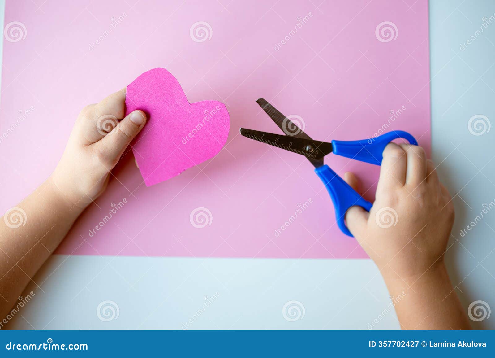 Childs Hands Cutting Pink Paper Heart with Scissors on Pink Background ...