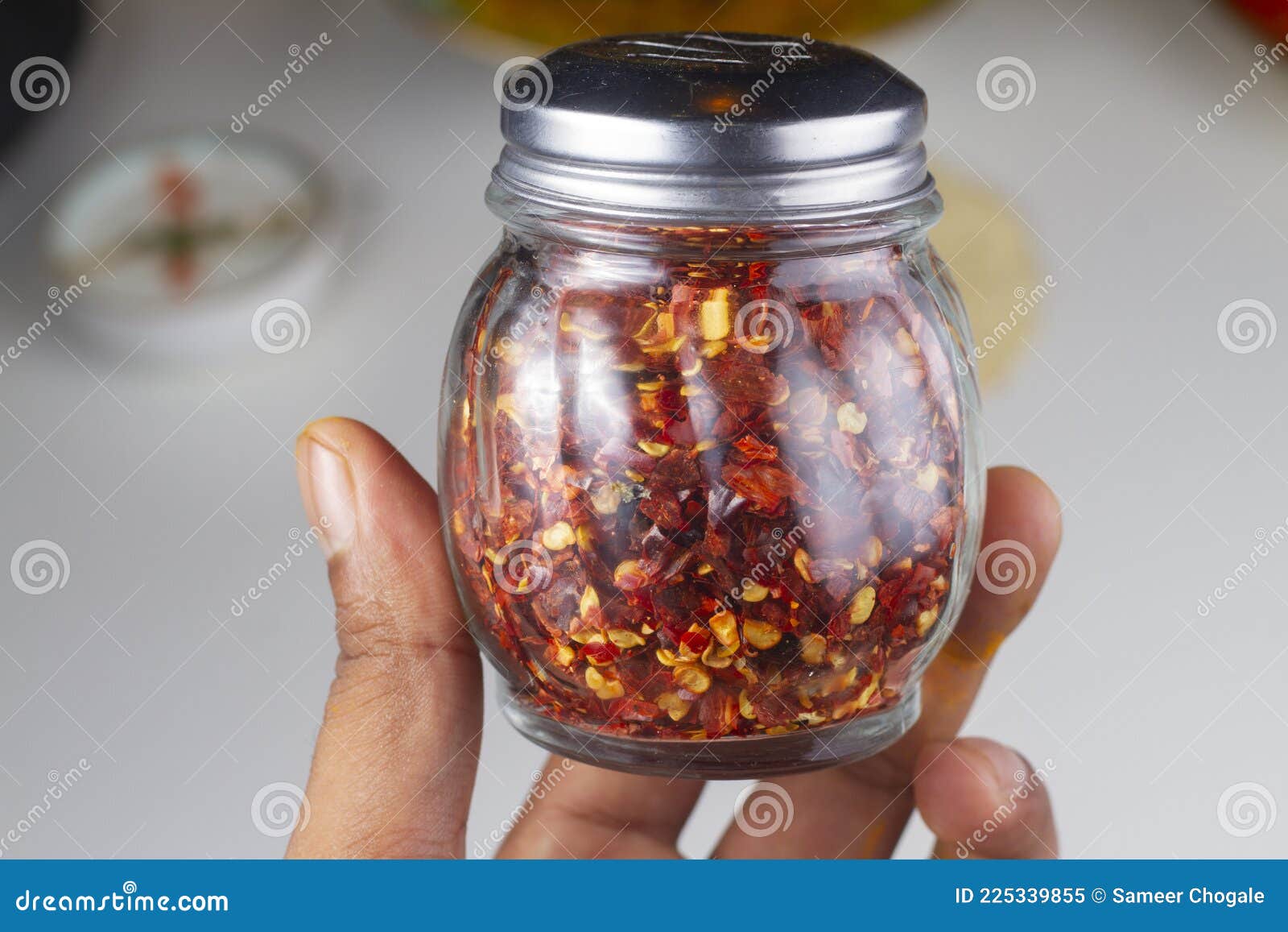 Chili Flakes Jar in Hand on Light Background Stock Image - Image of ...