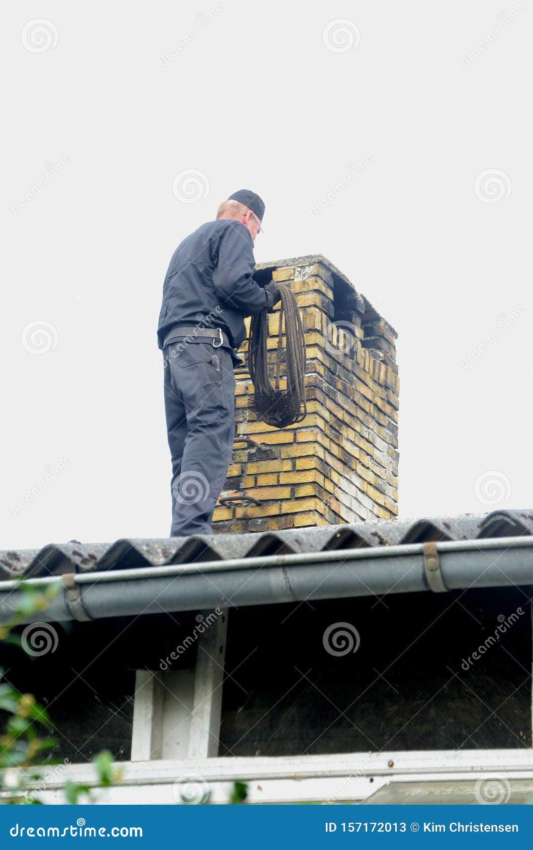 Chimney Sweeper at Work on a Roof with a Yellow Stone Chimney Editorial ...