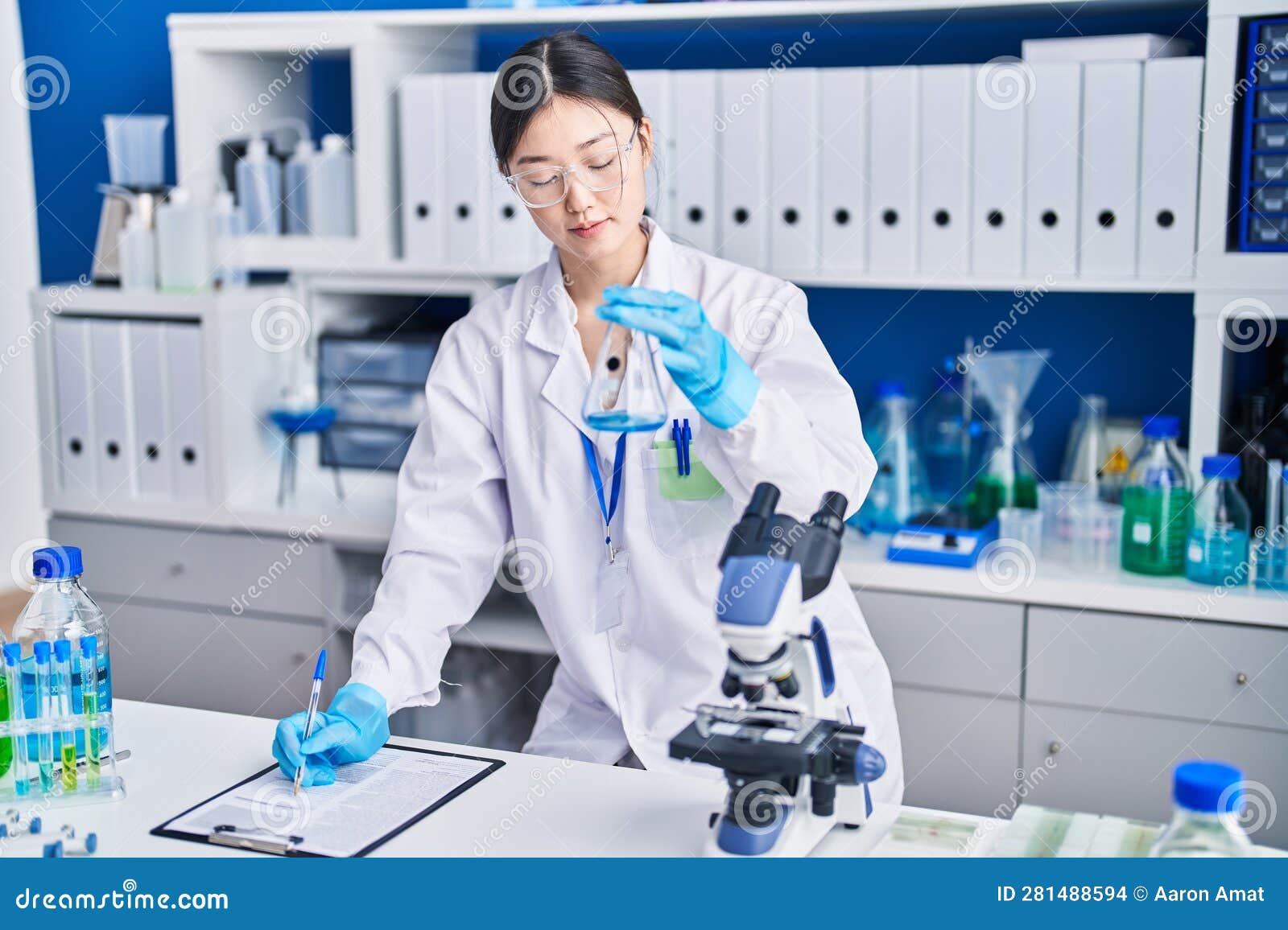 Chinese Woman Scientist Measuring Liquid Writing on Document at ...