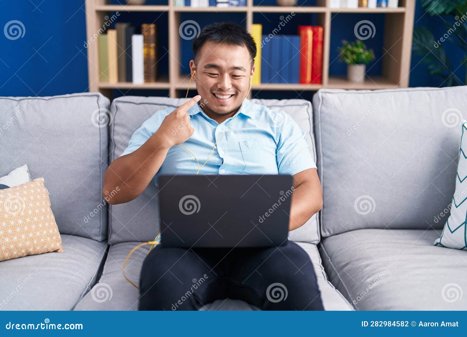 Chinese Young Man Using Computer Laptop Sitting on the Sofa Smiling ...
