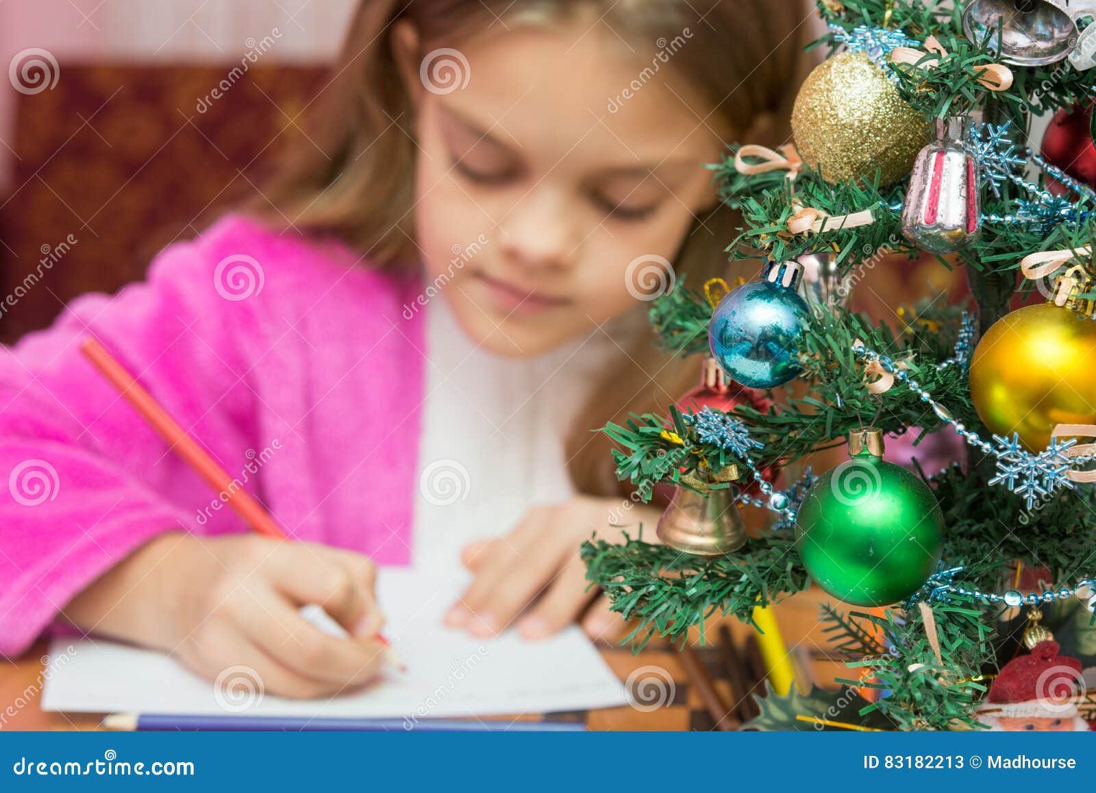 Christmas Tree in the Foreground, in Background a Girl Writing a Letter ...