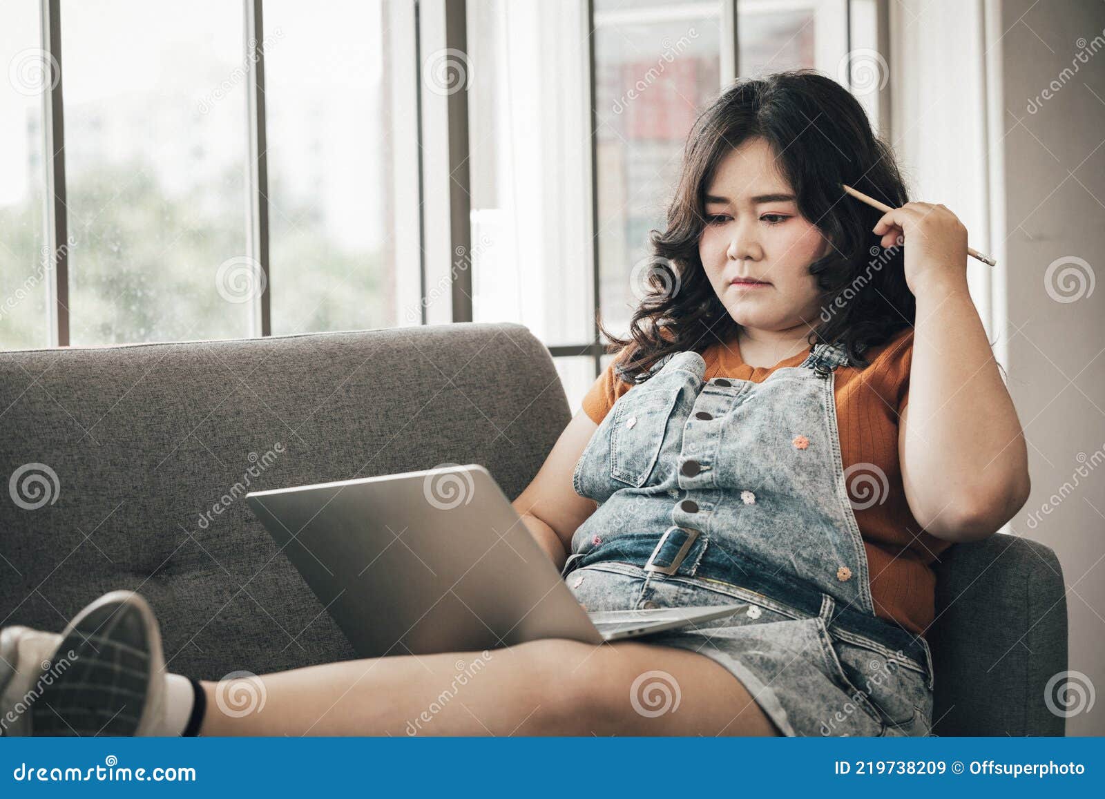 Chubby Woman Looking at Laptop Computer and Thinking for Work on Sofa ...
