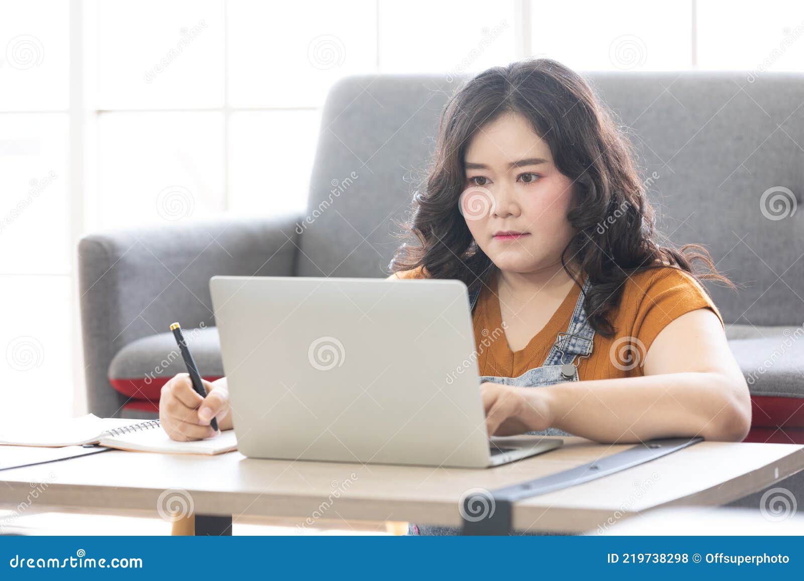 Chubby Woman Looking at Laptop Computer and Writing on Notebook for ...