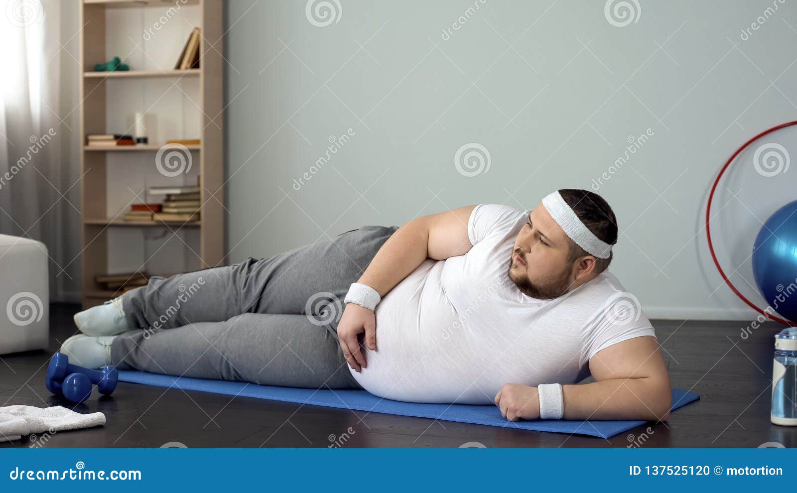 Chubby Man Lying on His Back, Watching and Repeating Online Exercises ...