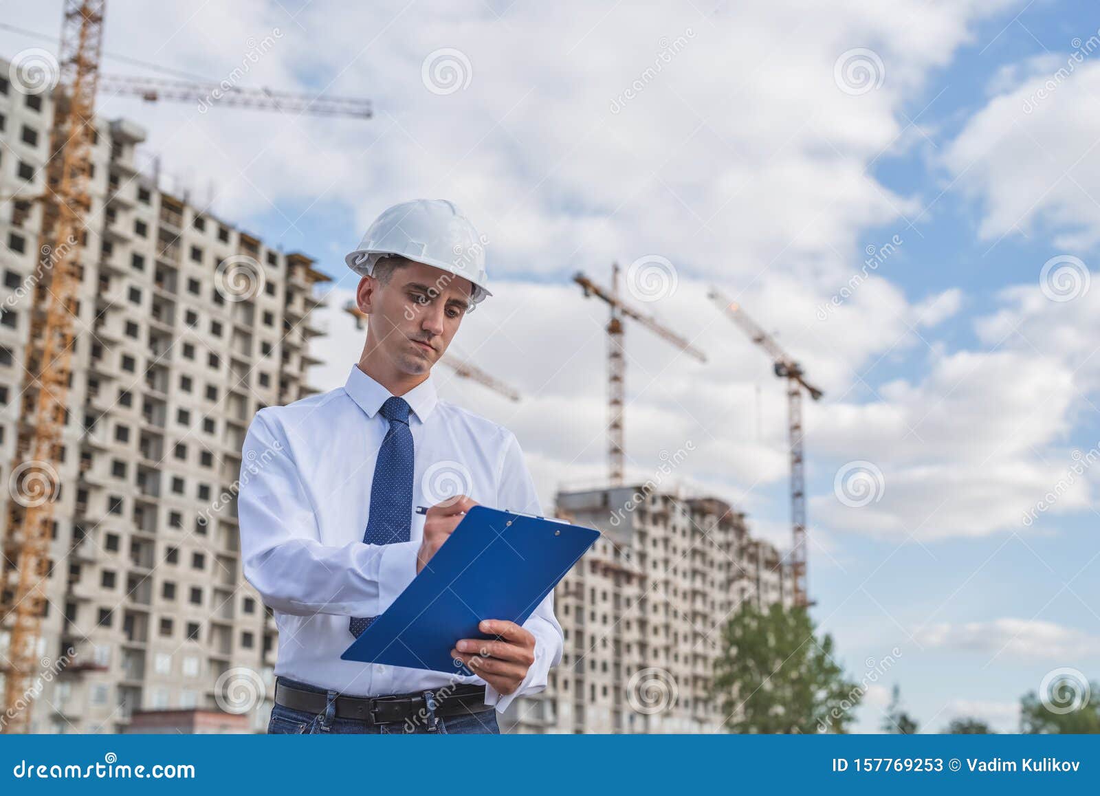 Civil Engineer in a White Helmet Makes Pencil Marks in the ...