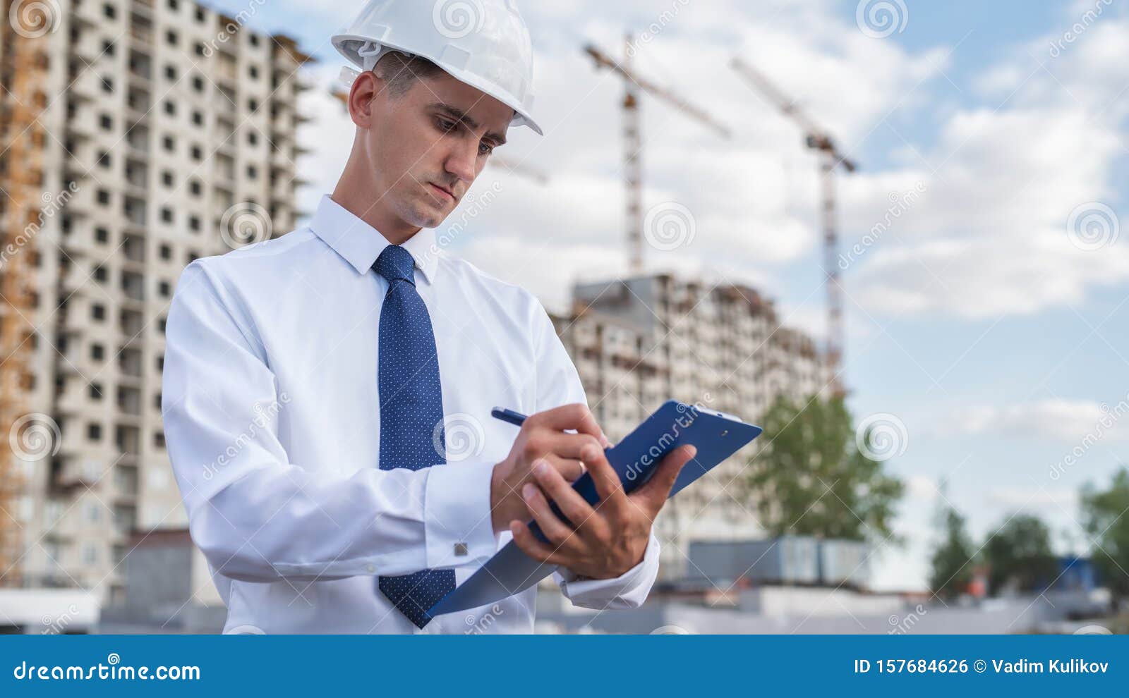 Civil Engineer in a White Helmet Makes Pencil Marks in the ...