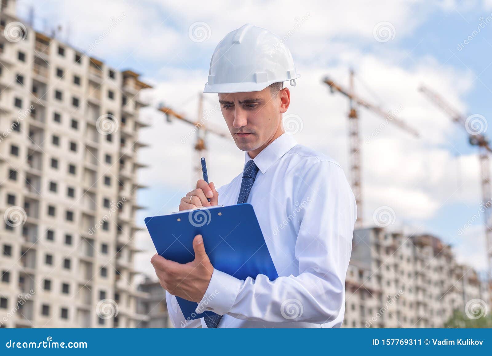 Civil Engineer in a White Helmet Makes Pencil Marks in the ...