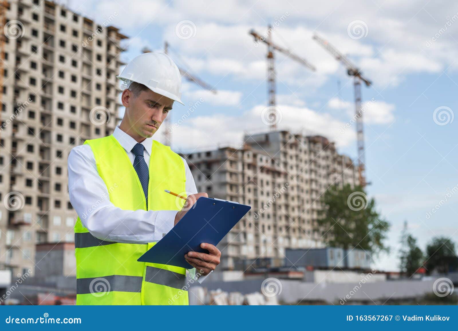 Civil Engineer in a White Helmet Makes Pencil Marks in the ...