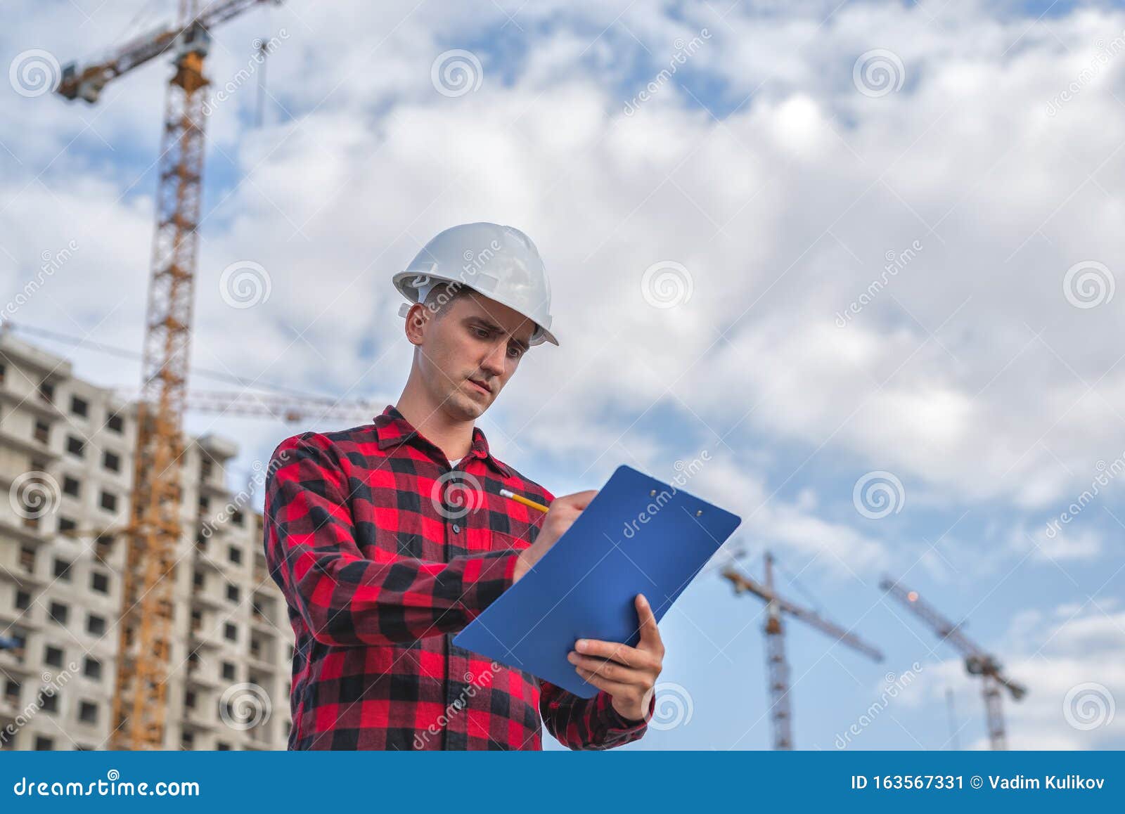 Civil Engineer in a White Helmet Makes Pencil Marks in the ...