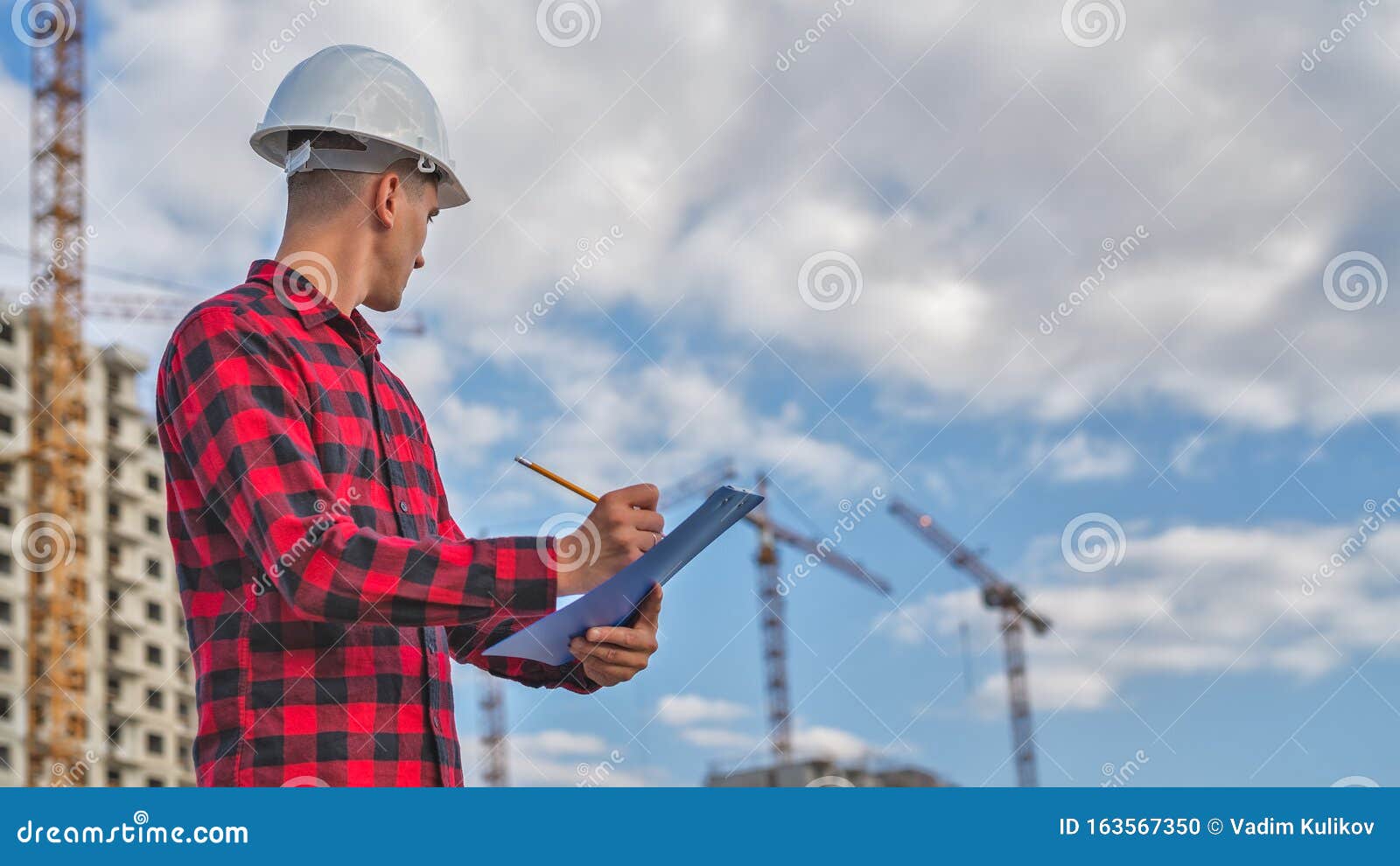 Civil Engineer in a White Helmet Makes Pencil Marks in the ...
