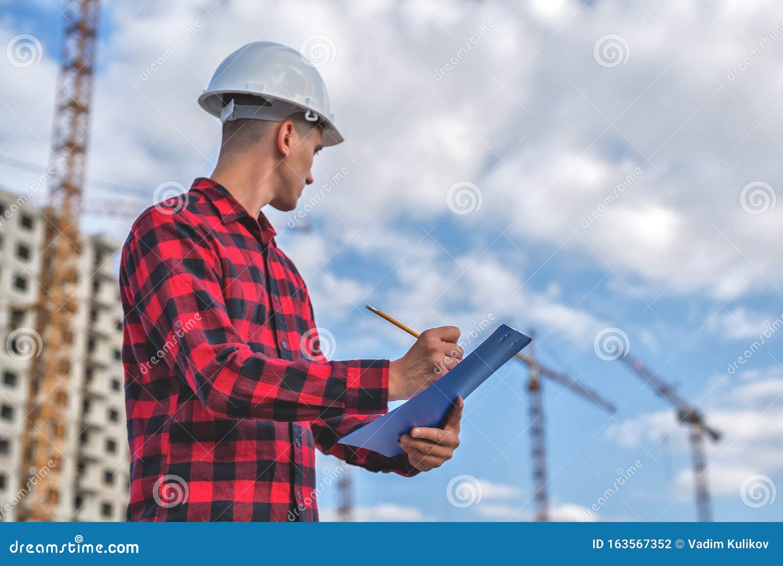 Civil Engineer in a White Helmet Makes Pencil Marks in the ...