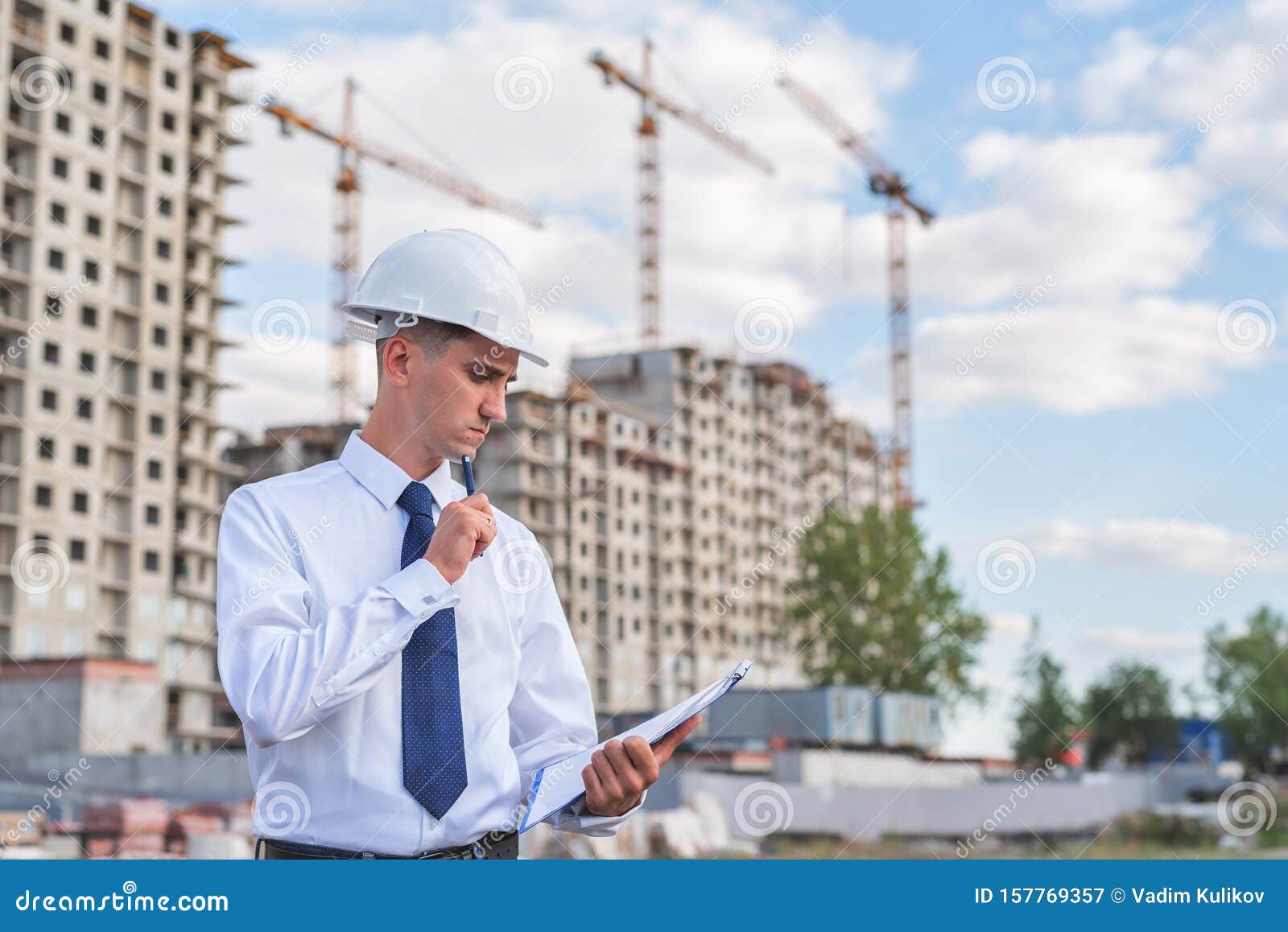 Civil Engineer in a White Helmet Makes Pencil Marks in the ...