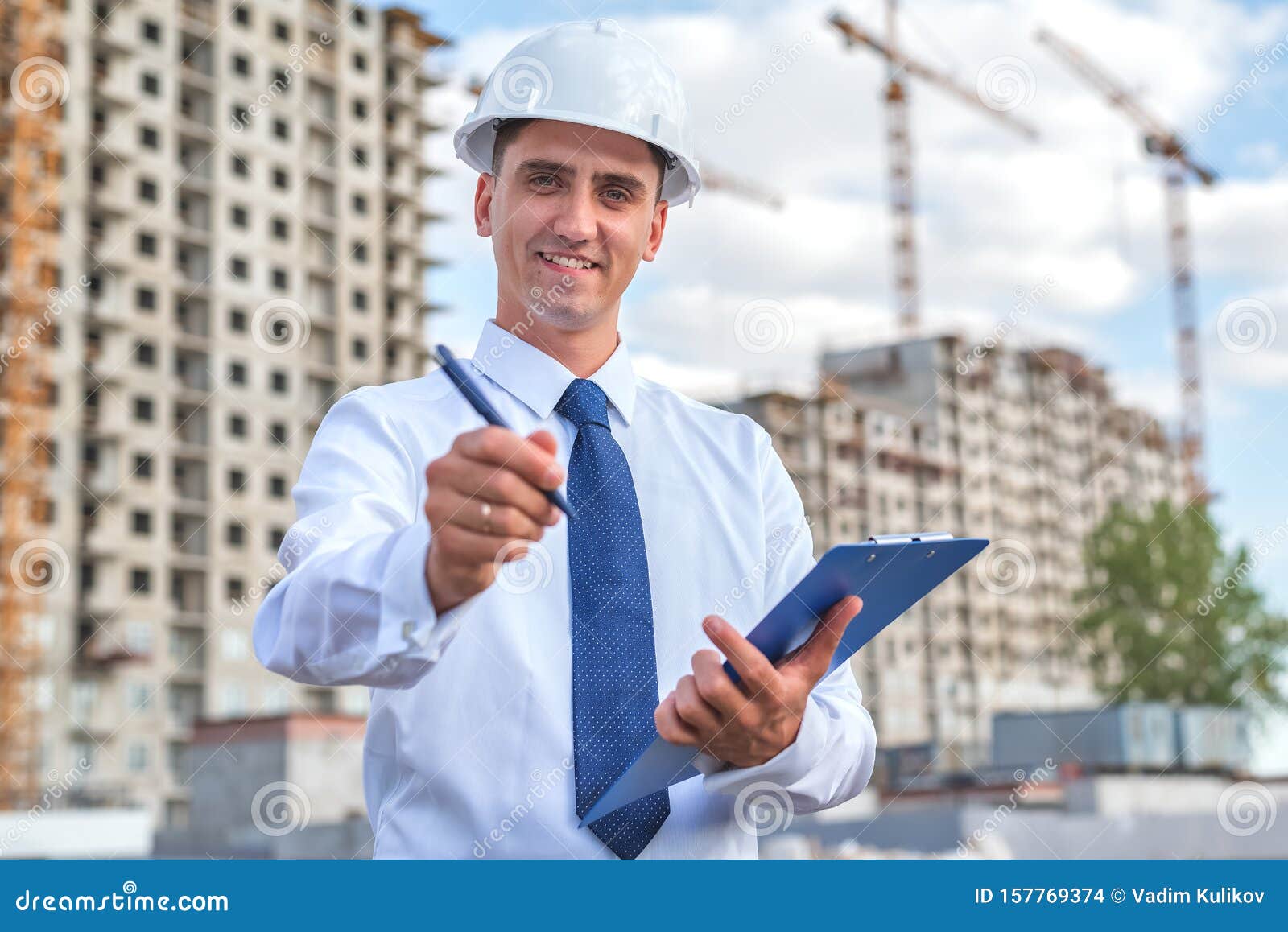 Civil Engineer in a White Helmet Makes Pencil Marks in the ...