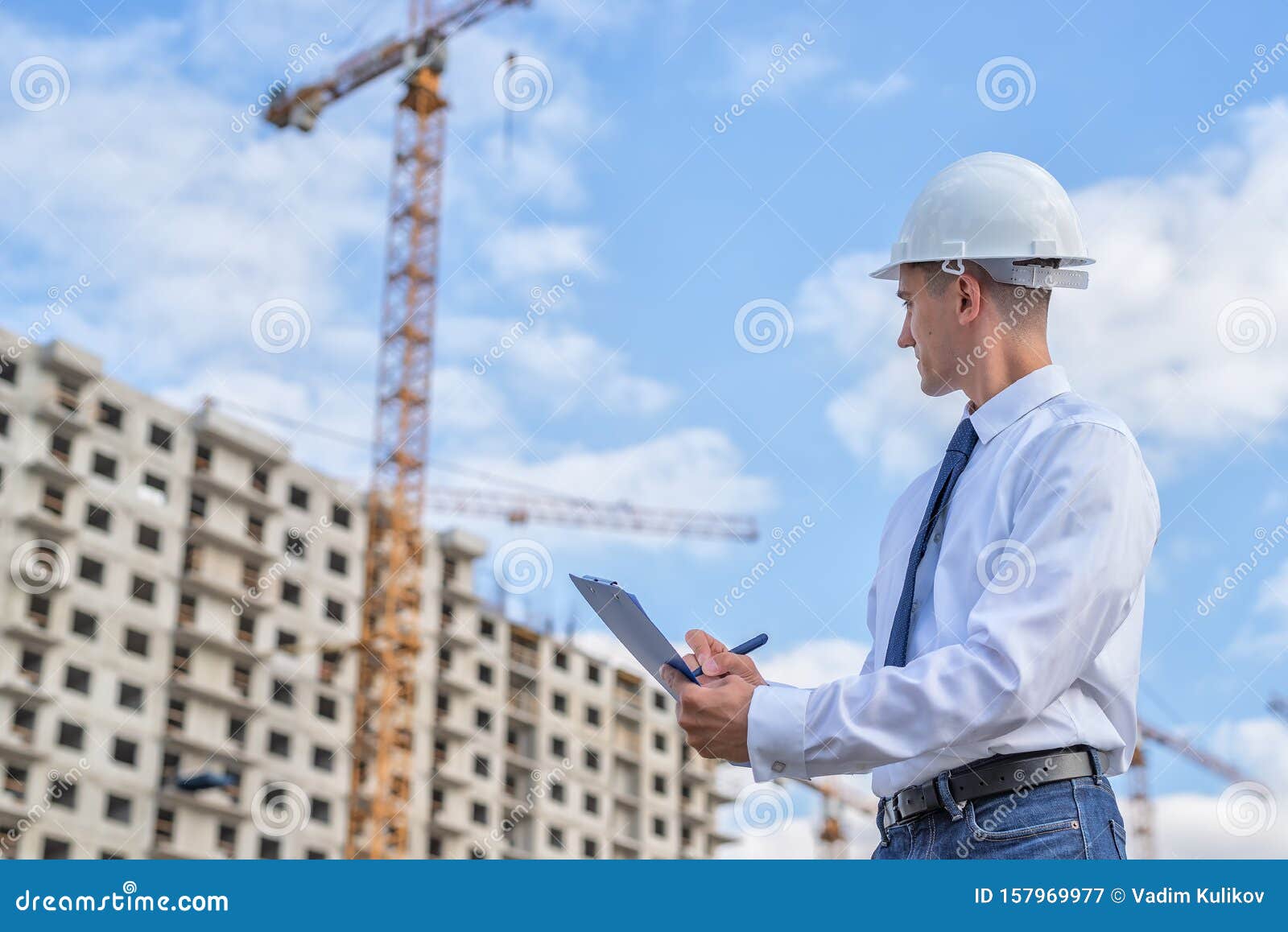 Civil Engineer in a White Helmet Makes Pencil Marks in the ...