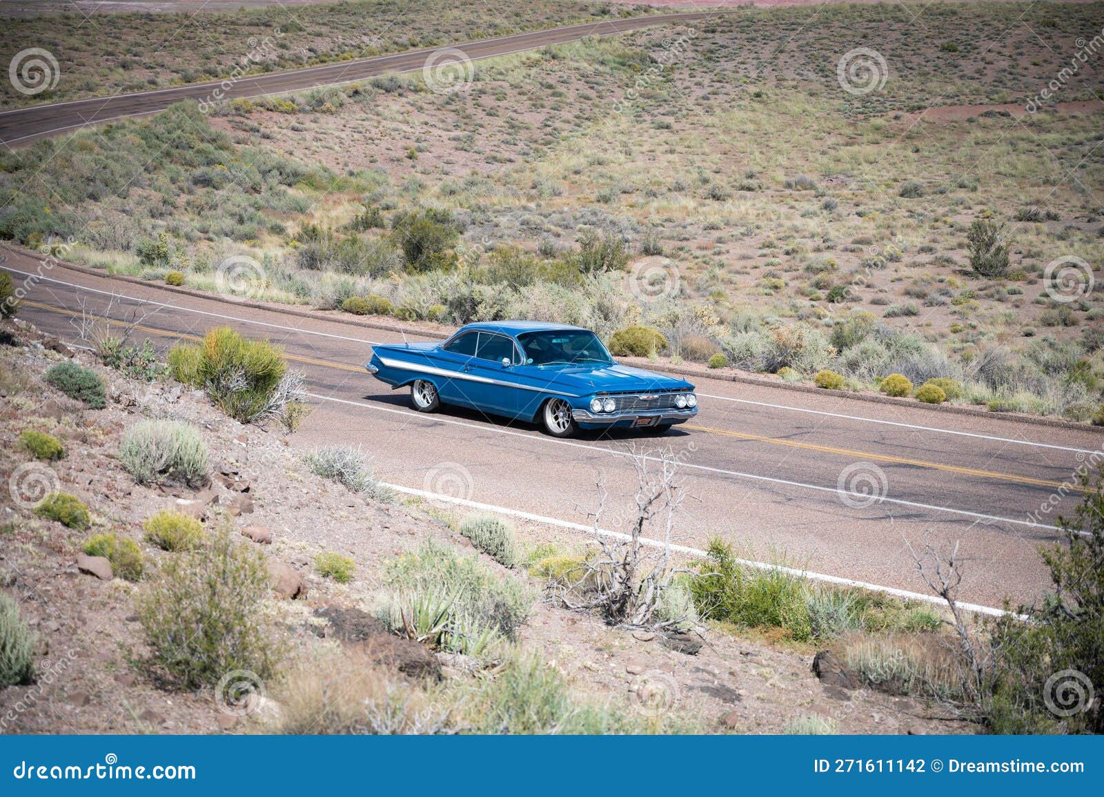 Classic Blue Car is Driving Down a Desert Highway, with Hills Visible ...
