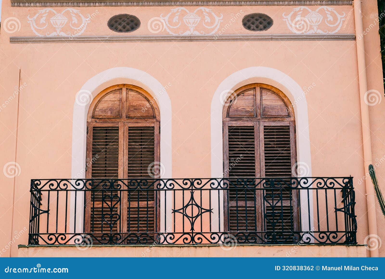 Classic European Pink Facade with Wrought Iron Balcony and Arched ...