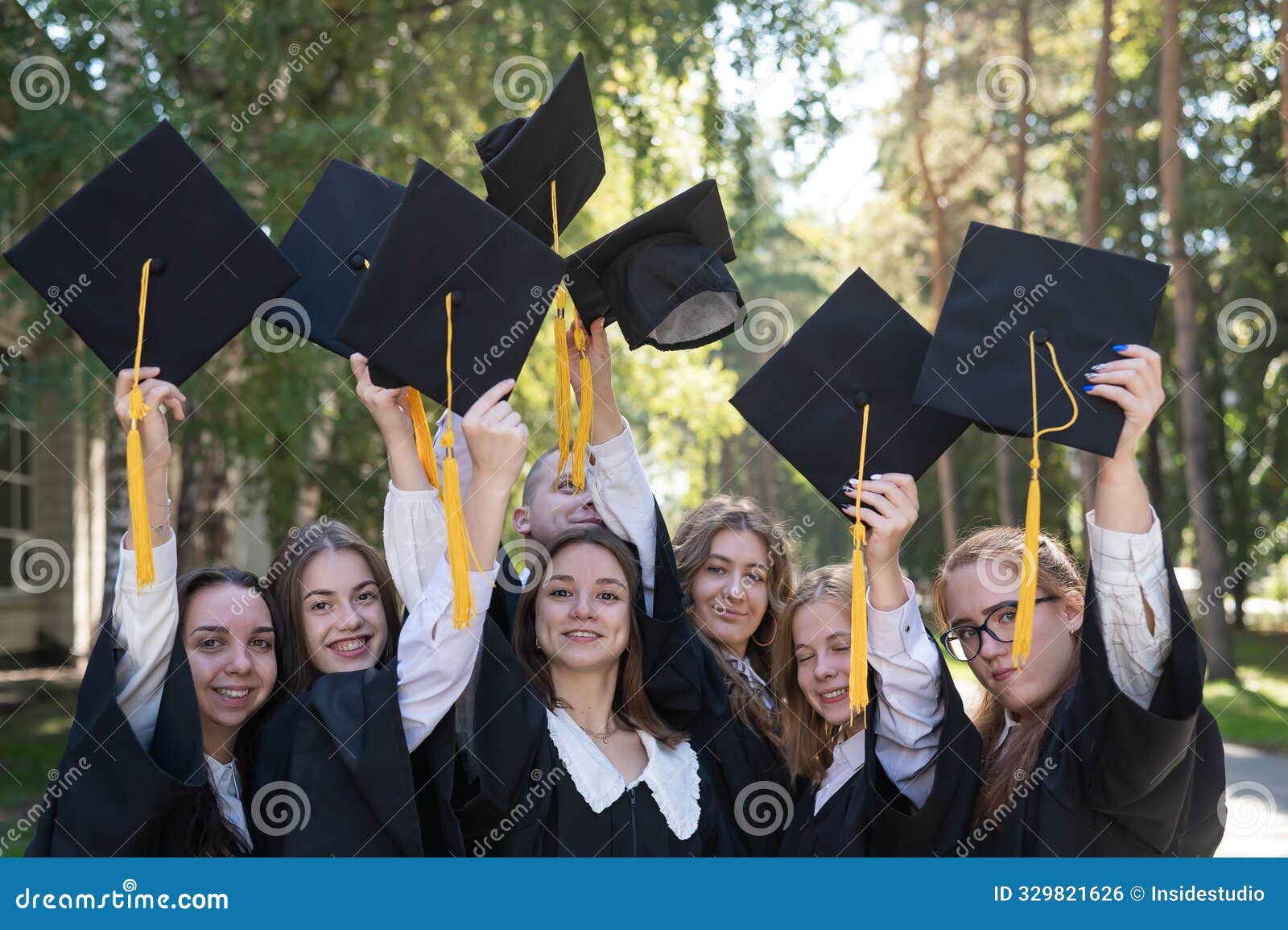 Classmates in Graduation Gowns Throwing Hats Outdoors. Stock Photo ...