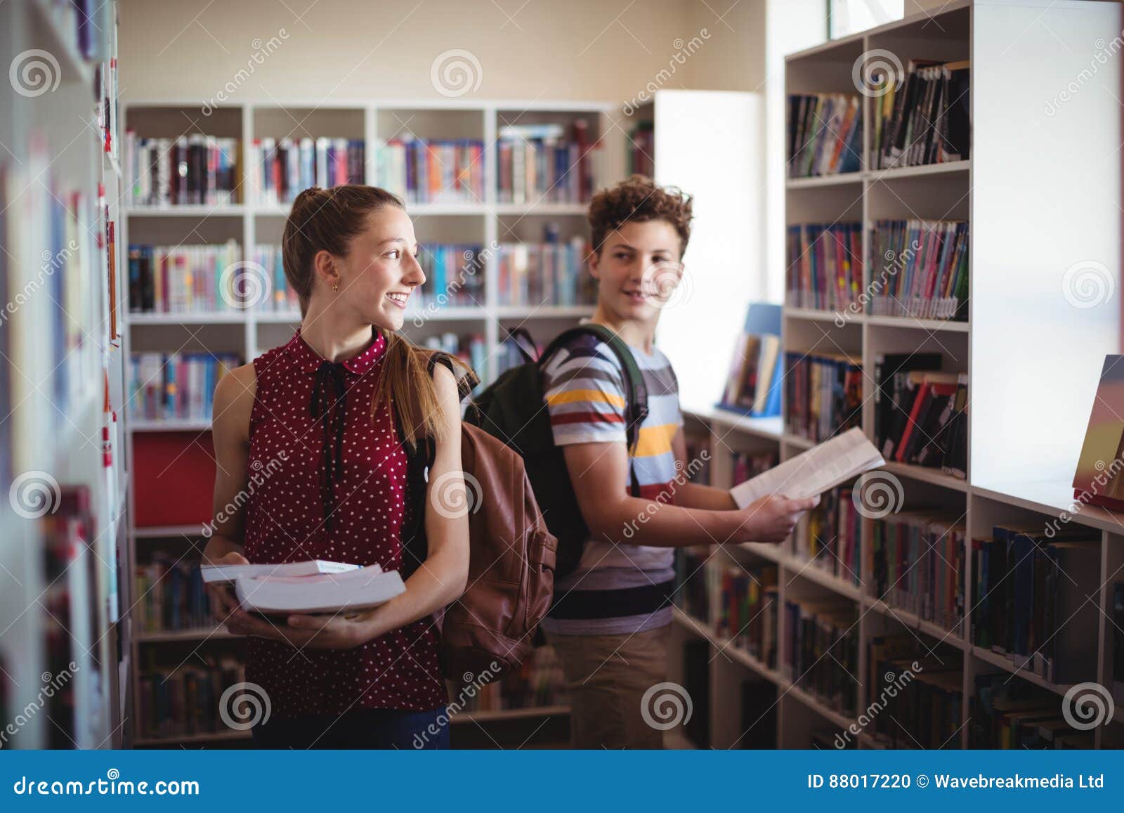 Classmates Interacting while Selecting Book in Library Stock Photo ...